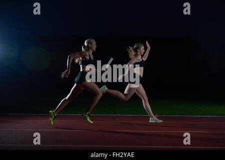 athletic runners passing baton in relay race Stock Photo - Alamy