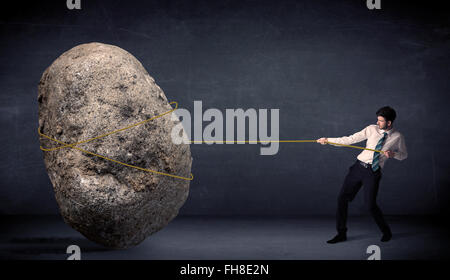 Businessman pulling huge rock with a rope Stock Photo - Alamy