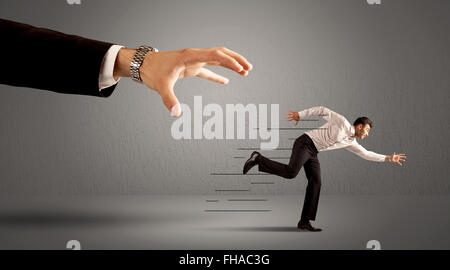 Businessman running away from a huge hand Stock Photo - Alamy