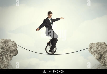 Brave business man riding an mono cycle between cliffs Stock Photo - Alamy