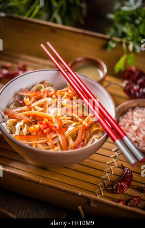 Tasty rice noodles in bowl and chopsticks on red table, closeup Stock ...