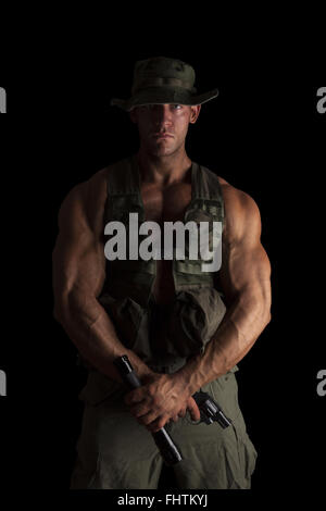 Serious young muscular soldier with gun and flashlight in green uniform ...