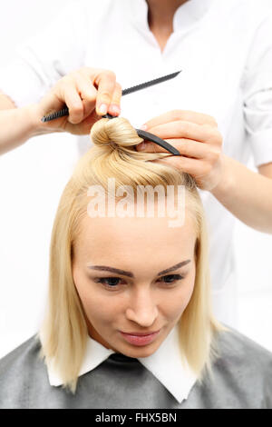 Combing the hair of a young woman during coloring hair in pink color at ...
