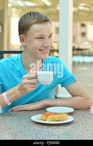 Teenager boy drinking a cup of coffee over isolated pink background ...