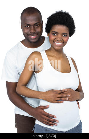 Young couple expecting a baby standing over pink background doing ...