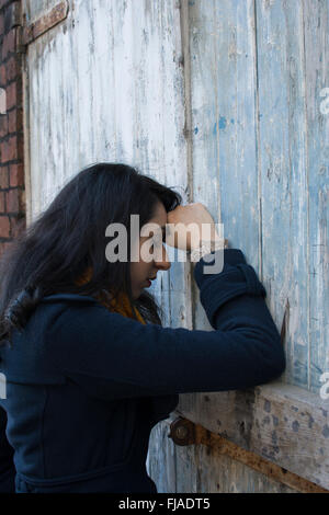 Profile of a woman leaning against a door and looking away Stock Photo ...