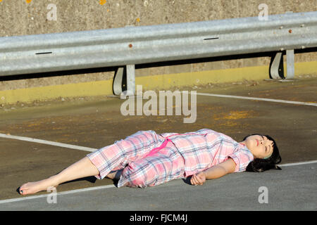 July 2015 - Young woman playing dead in her pajamas on top of a multi ...