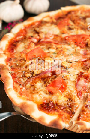 Delicious Italian pizza sliced with bacon, cheese, tomato, capsicum on ...