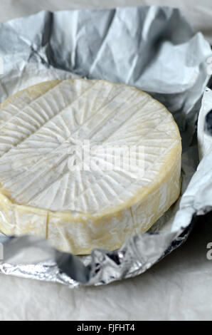 Whole round Camembert cheese cut in half showing ripe runny interior ...