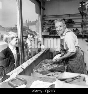 Shoe repairer mending shoes in cobblers shop working on machine to ...