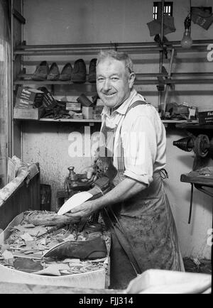 Shoe repairer mending shoes in cobblers shop working on machine to ...