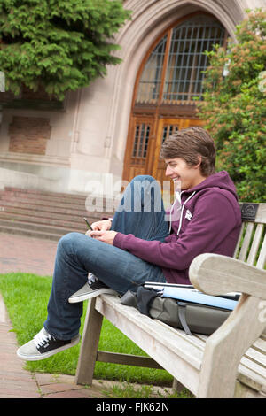 Smiling male college student using mobile phone Stock Photo - Alamy