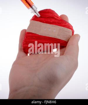 Hand injecting love into heart in plaster on white background Stock ...
