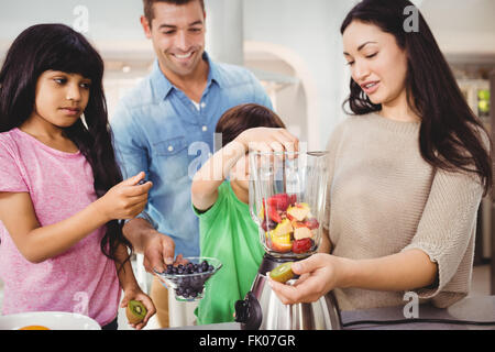 Happy family preparing fruit juice at table Stock Photo - Alamy