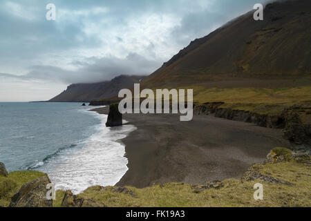 Horizontal view of an Icelandic beach with a huge rock formation in the ...