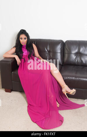 Woman sat on leather sofa Stock Photo - Alamy