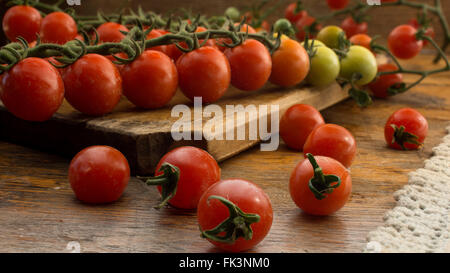 Cherry tomatoes on display on wooden chopping board and wooden table ...