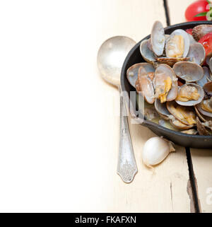 fresh clams stewed on an iron skillet over wite rustic wood table Stock ...