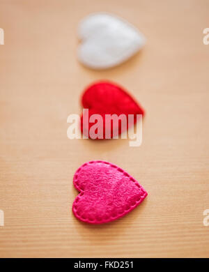 Three red hearts in a row cut from paper on white background, craft ...