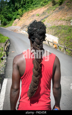 Rear view of man with green dreadlocks holding fluffy white dog on ...
