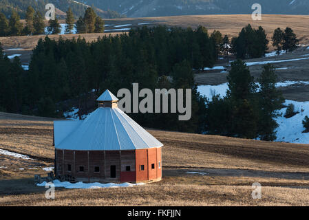 Round barn near Flora, Oregon. An elk herd is visible on the open slope ...