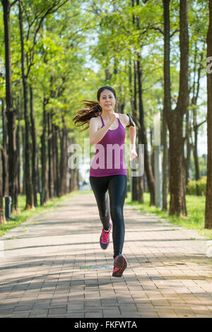 Young woman jogging outside in a pine forest. Young woman doing workout ...