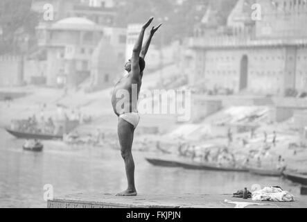 At sunrise man doing yoga postures,poses,routine facing rising sun.On ...