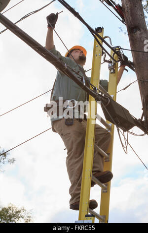 Cable lineman climbing a ladder to repair transmission line Stock Photo ...