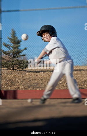 Caucasian boy hitting baseball on field Stock Photo - Alamy