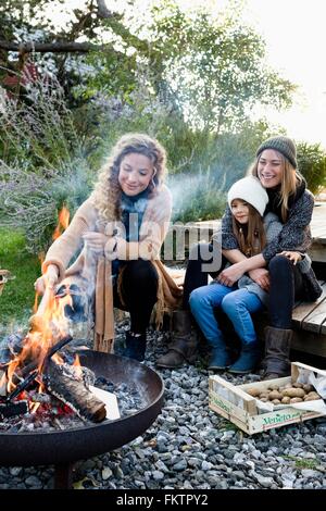 Family relaxing by fire outdoors Stock Photo - Alamy