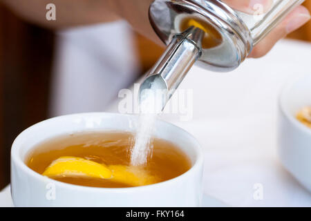 Adding white granulated sugar to cup of tea Stock Photo - Alamy