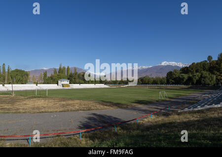 Soccer pitch and snow capped mountains in Toktogul, Kyrgyzstan, Asia ...