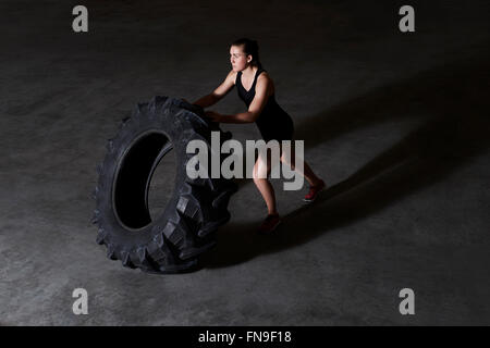 Woman pushing a tire in the gym Stock Photo - Alamy