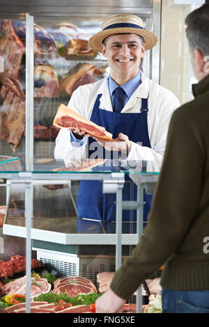 A shop assistant in uniform and hat on the patisserie counter at ...