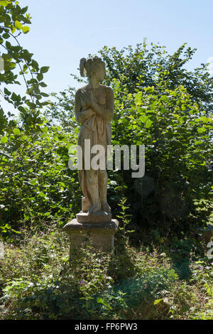 A classical statue of a woman draped in flowing garments, holding a ...