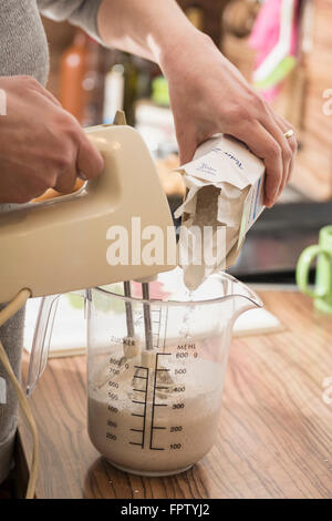 Person holding a measuring cup with sugar Stock Photo - Alamy