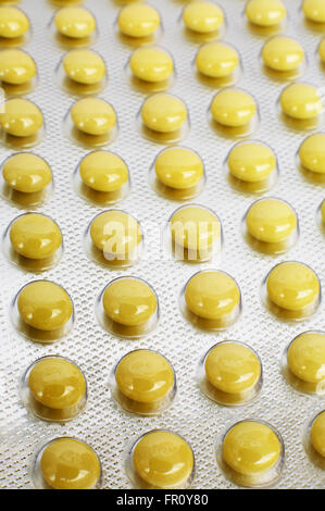 Yellow and round pills in a factory packing Stock Photo - Alamy