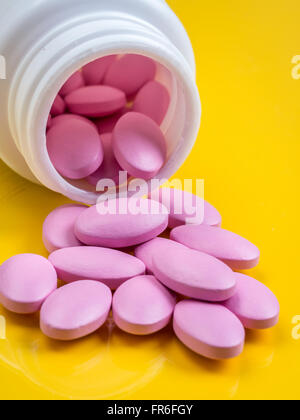 Pink medical pills and tablets spilling out of a drug bottle ...