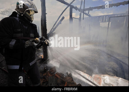 fireman with hose putting out fire Stock Photo - Alamy
