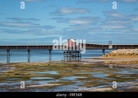 industrial loading jetty with red house, shallow water speckled with ...
