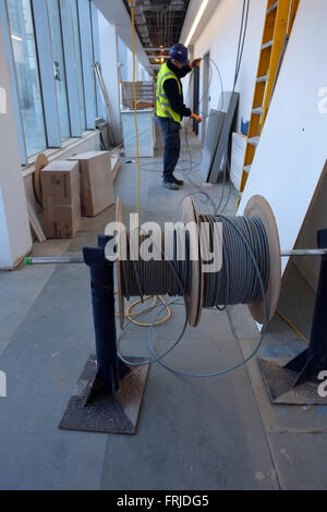 Male electrician pulling power cable from cable drum in workshop Stock ...