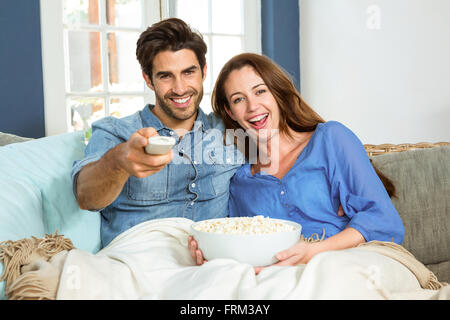 Young couple having popcorn while watching television Stock Photo - Alamy