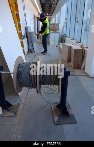 Male electrician pulling power cable from cable drum in workshop Stock ...