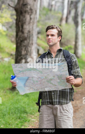young man holding map with backpack sitting on platform at train ...