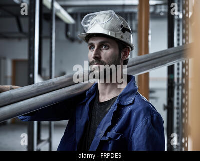 worker carrying pipes on his shoulder on construction site Stock Photo ...