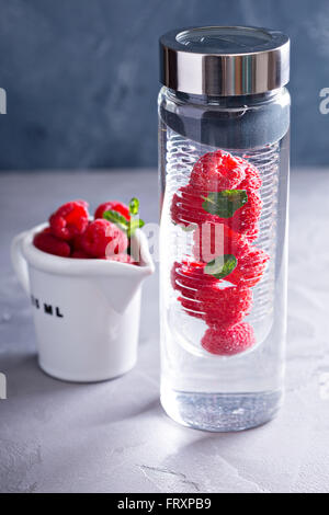 Fresh ripe raspberries with green mint leaves on black plate against ...