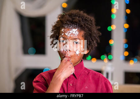 Kid with cake-covered face. Afro boy covered in cake. Not greedy at all ...