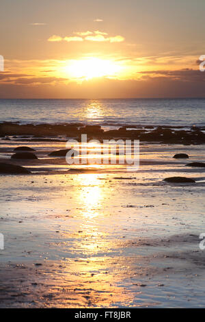 beach and wooden groyne at sunset with large pools of water and cloud ...