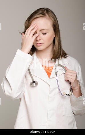 Stressed female doctor with hand on forehead isolated. Exhausted young ...
