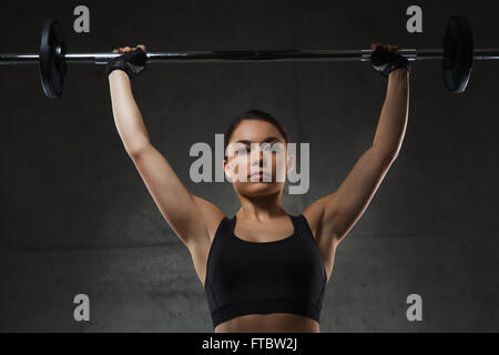 young woman flexing muscles with barbell in gym Stock Photo - Alamy